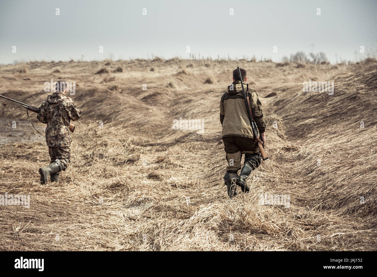 Hunters running across dry rural field during hunting Stock Photo - Alamy