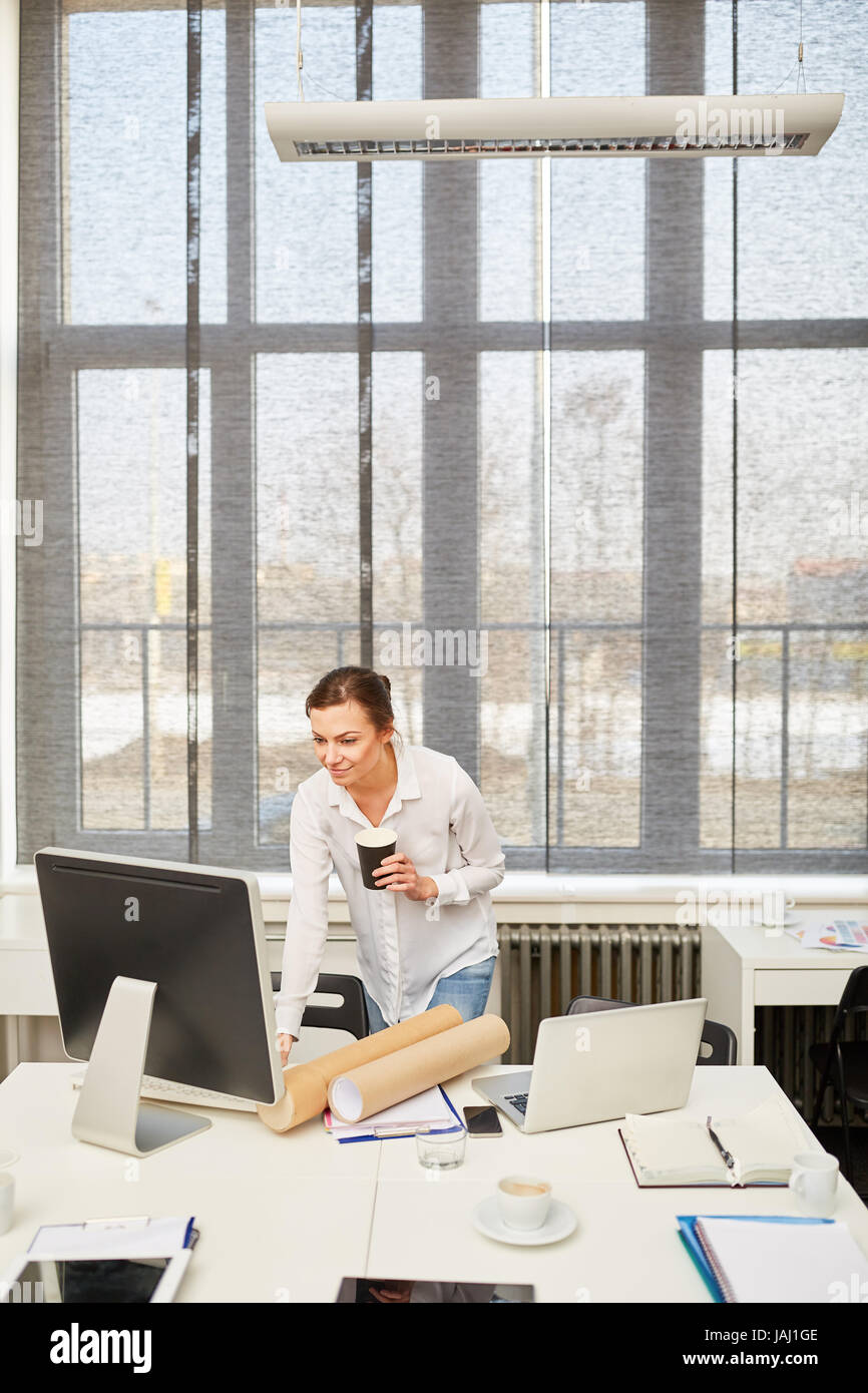 Young business woman looking at computer monitor in start-up place of ...