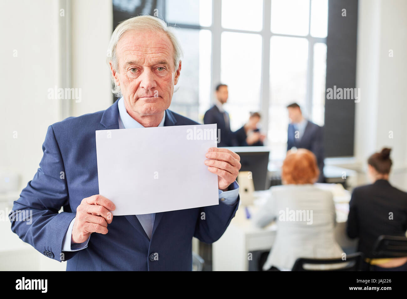 Senior man looking concerned holds empty sign in office Stock Photo - Alamy