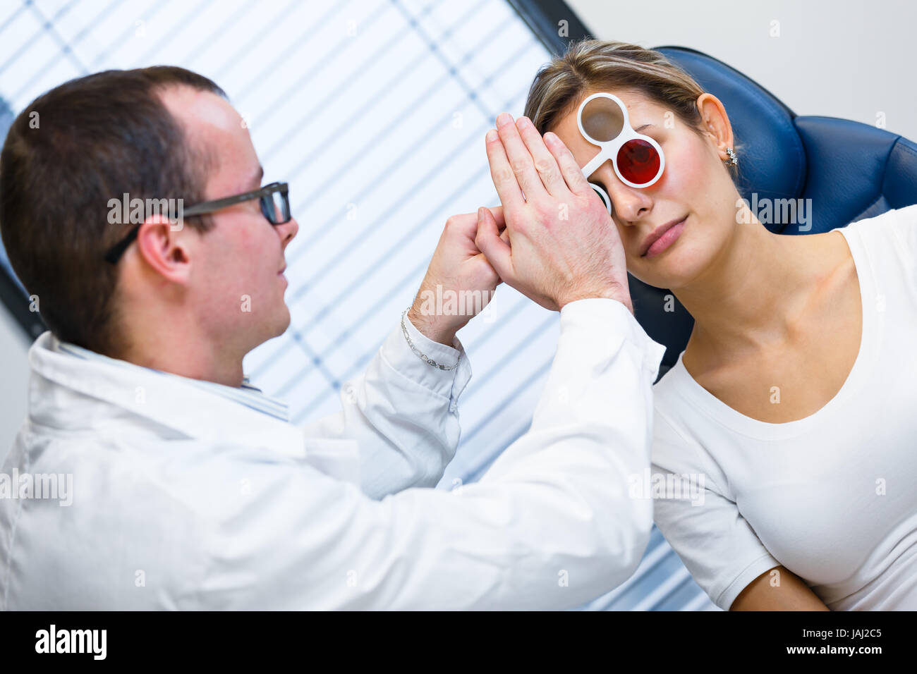 Optometry concept - pretty young woman having her eyes examined by an ...