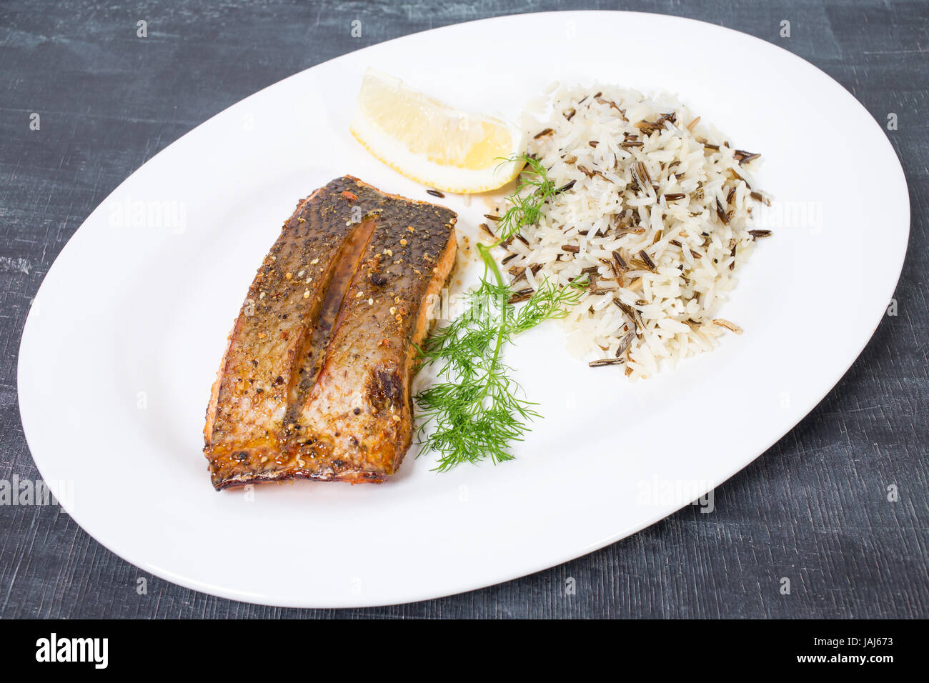 Griiled salmon fillet with basmati rice and lemon. Plate located on a ...