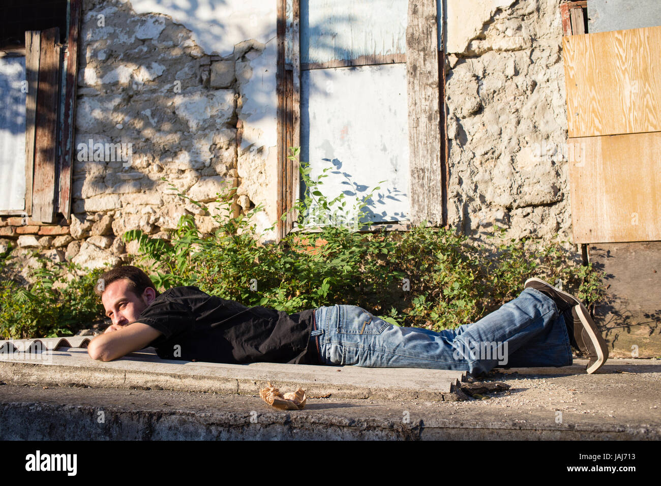 Man and a city. The tramp is lying on the concret ramp Stock Photo - Alamy