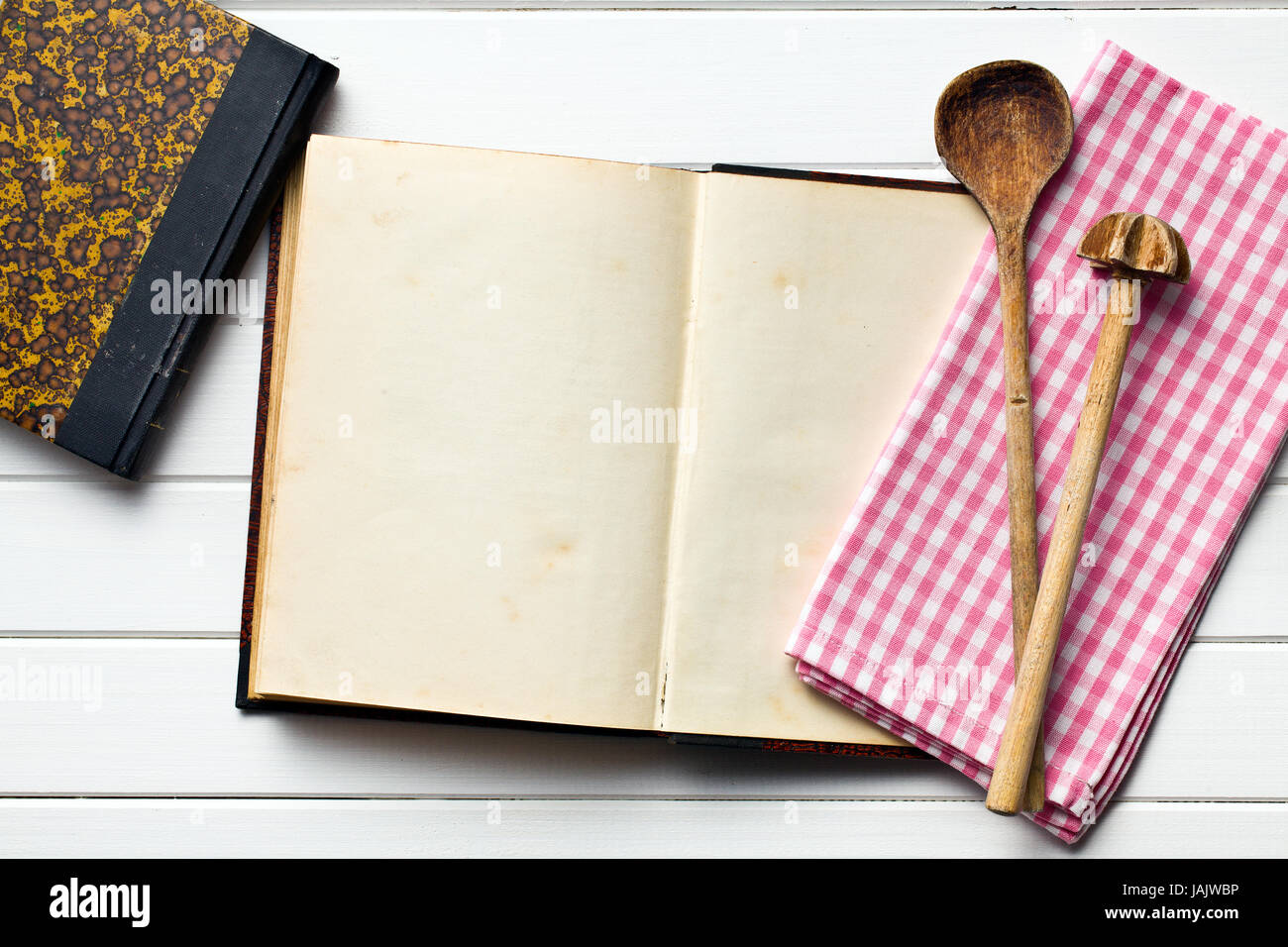 top view of old recipe book with kitchenware and napkin on white wooden ...