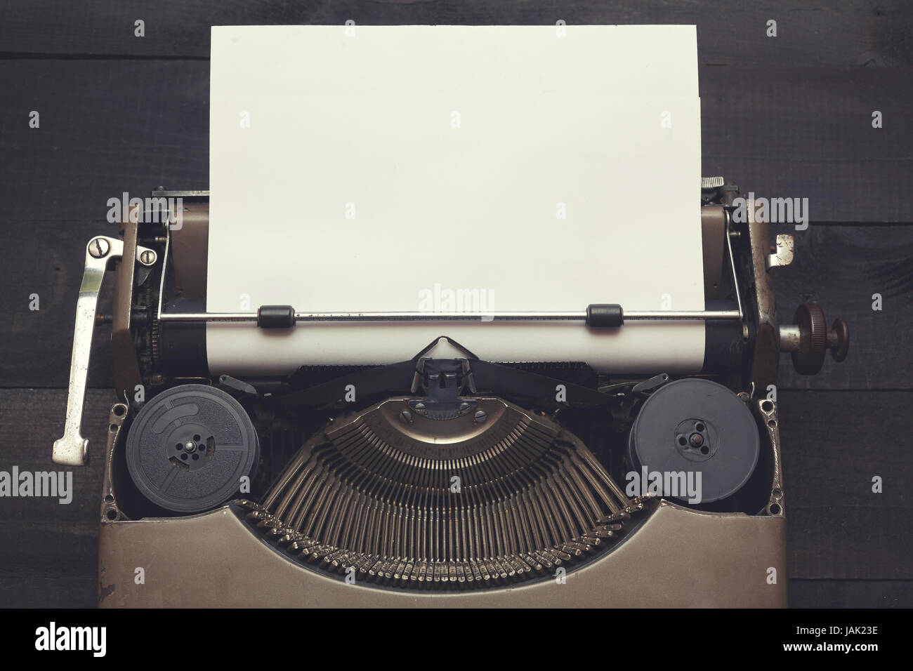 Old, well-worn typewriter on a black wooden background. Sheet of paper ...