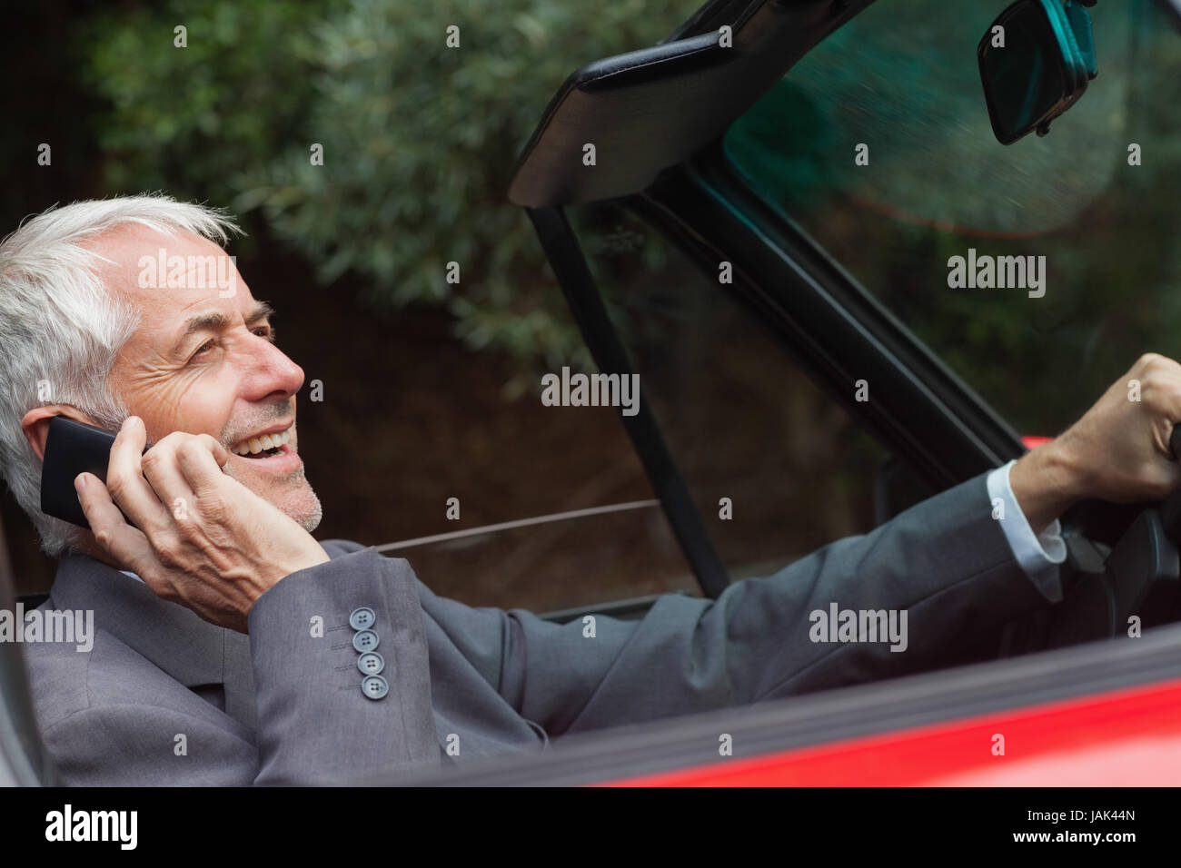 Happy businessman on the phone driving expensive car Stock Photo - Alamy