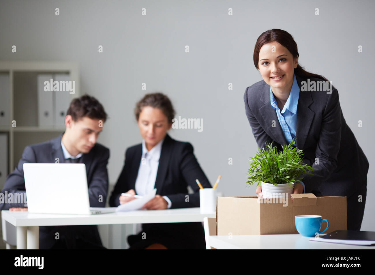 Portrait of smart businesswoman packing her things and looking at ...