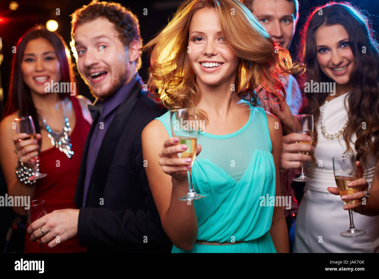 Portrait of cheerful girl with champagne flute dancing at party on ...