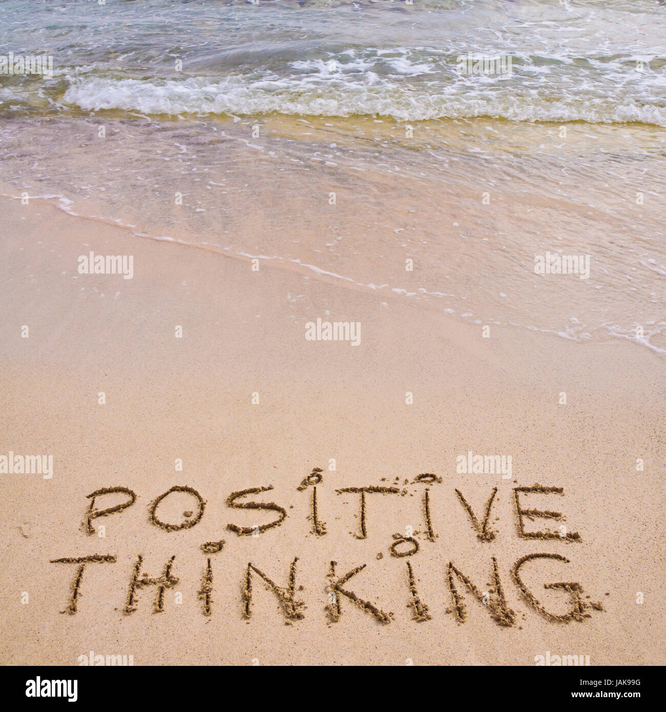 Positive Thinking message written on sand, with waves in background ...