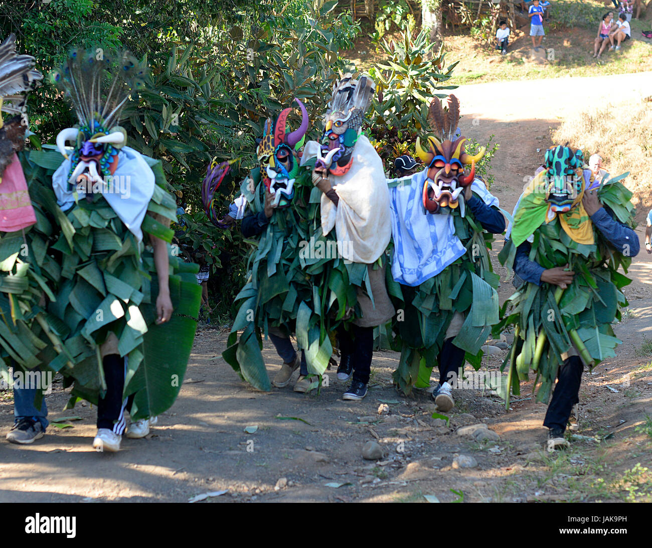 Devil's wearing masks walk up a hill during the Juegos de los Diablitos ...
