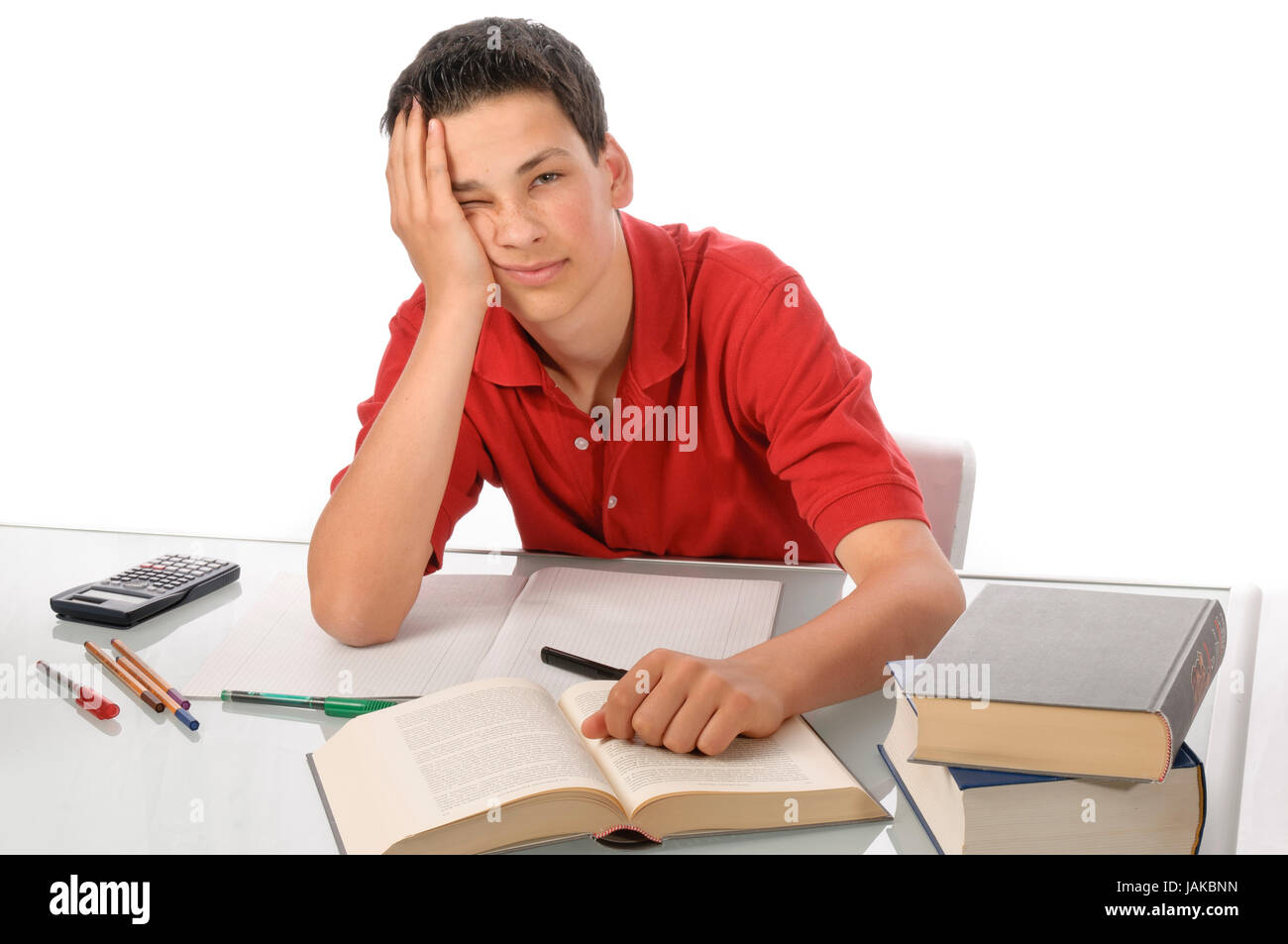 Junge sitzt erschöpft und frustriert über Hausaufgaben am Schreibtisch ...