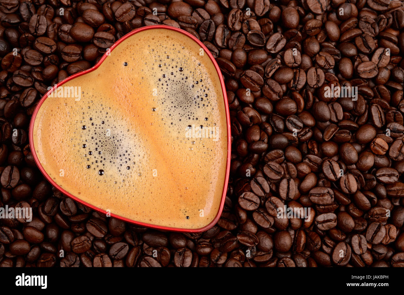 Heart shaped coffee cup on coffee beans background Stock Photo - Alamy