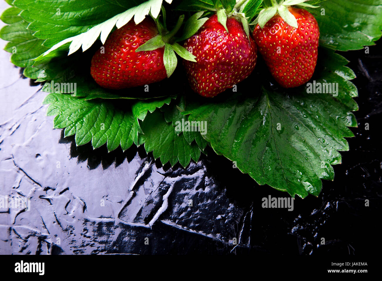 Wet strawberry with leaves on black background. Top view. Copy space ...