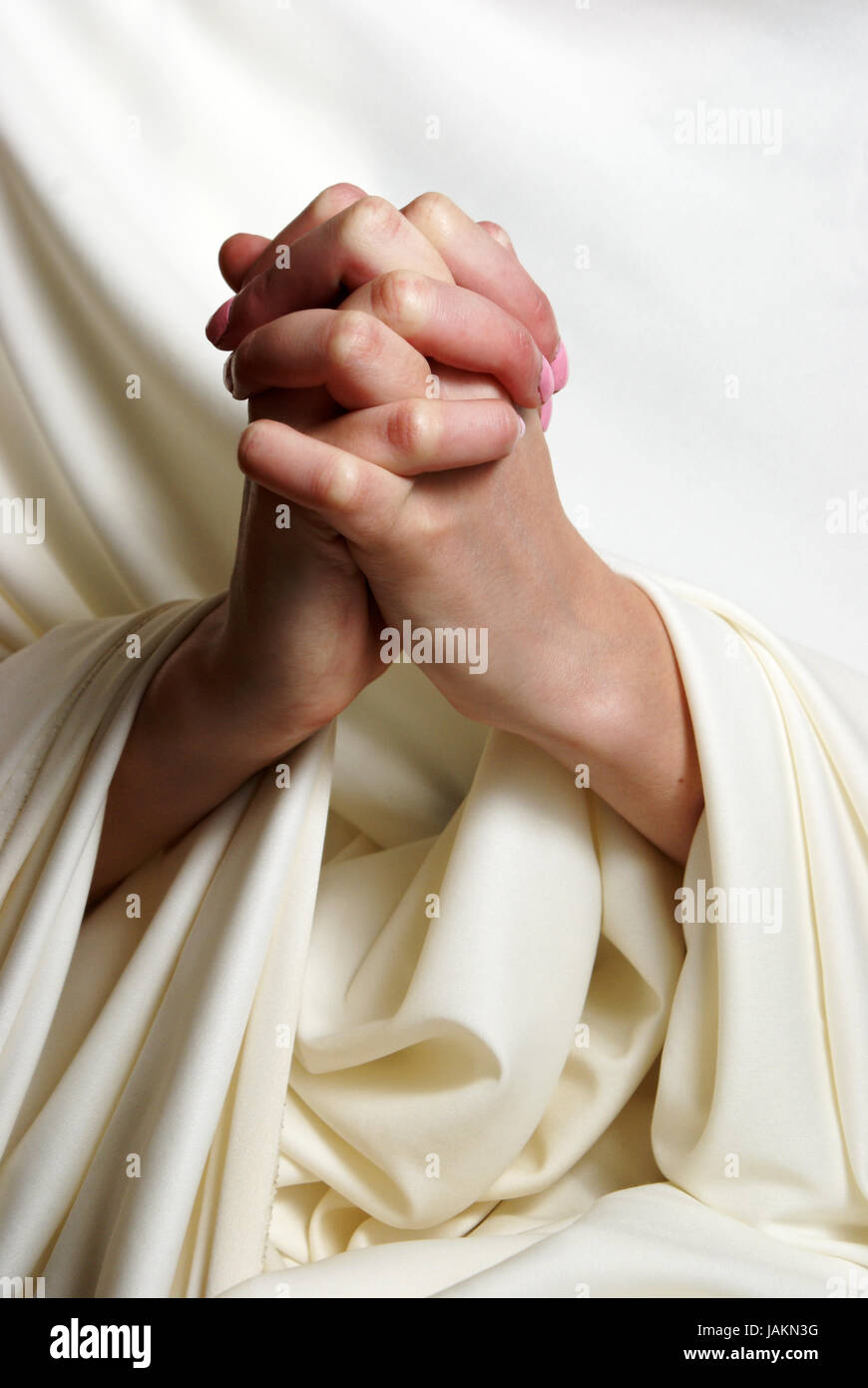 A young woman faithfully brings her hands together in essence of prayer ...