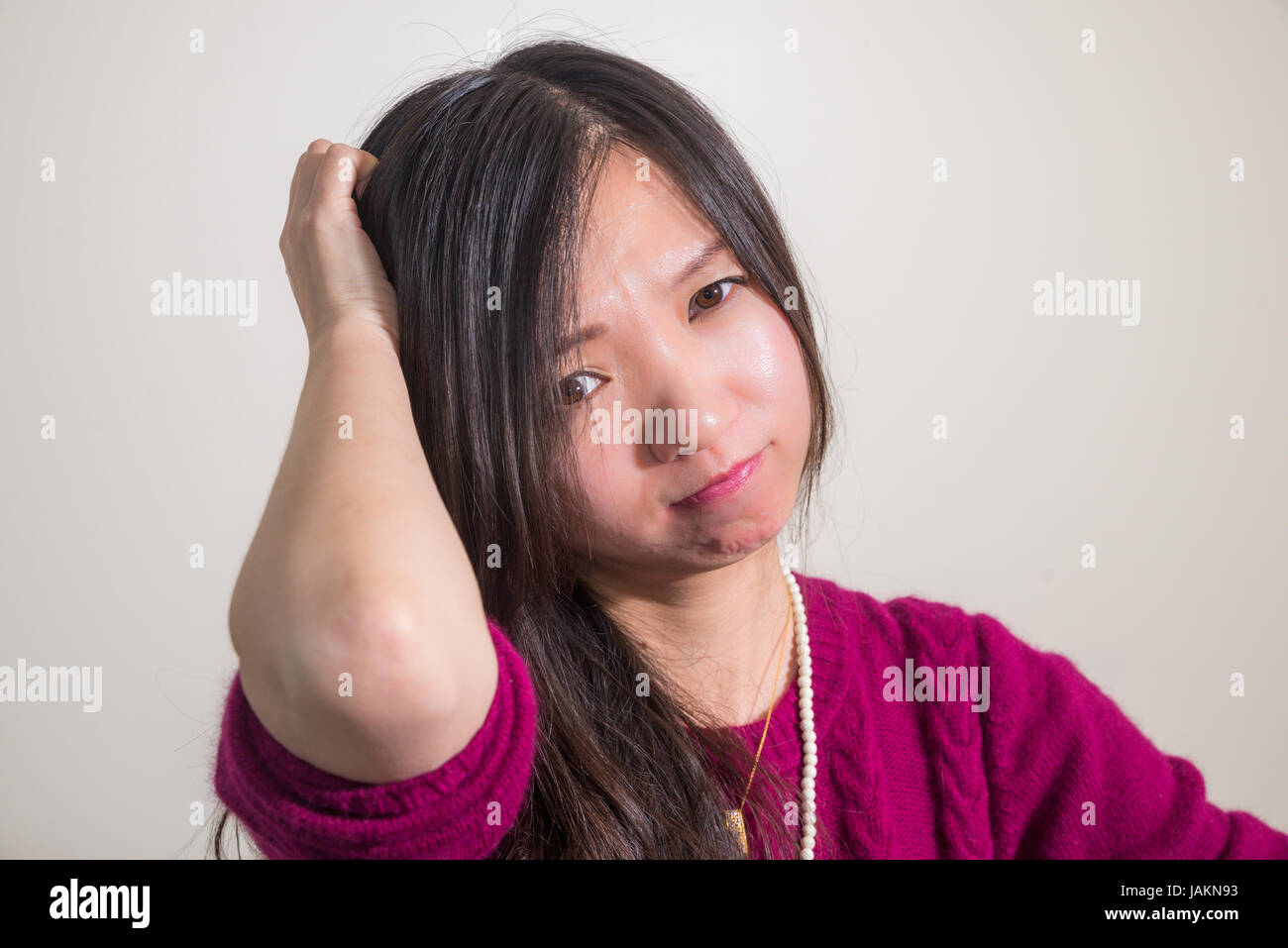 Young woman scratching head looking confused Stock Photo - Alamy