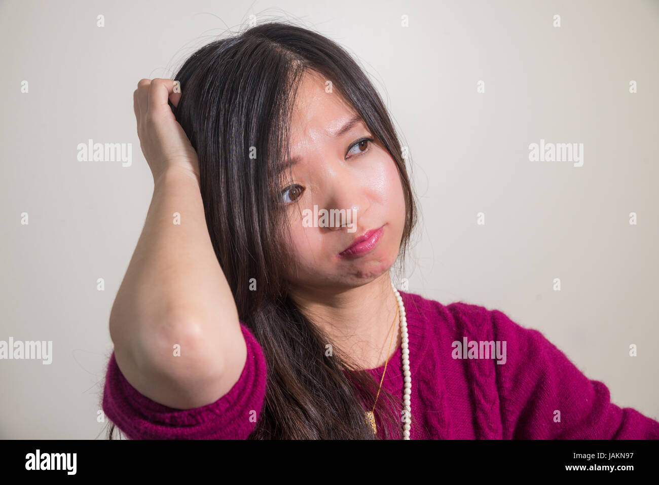Young woman scratching head looking confused Stock Photo - Alamy