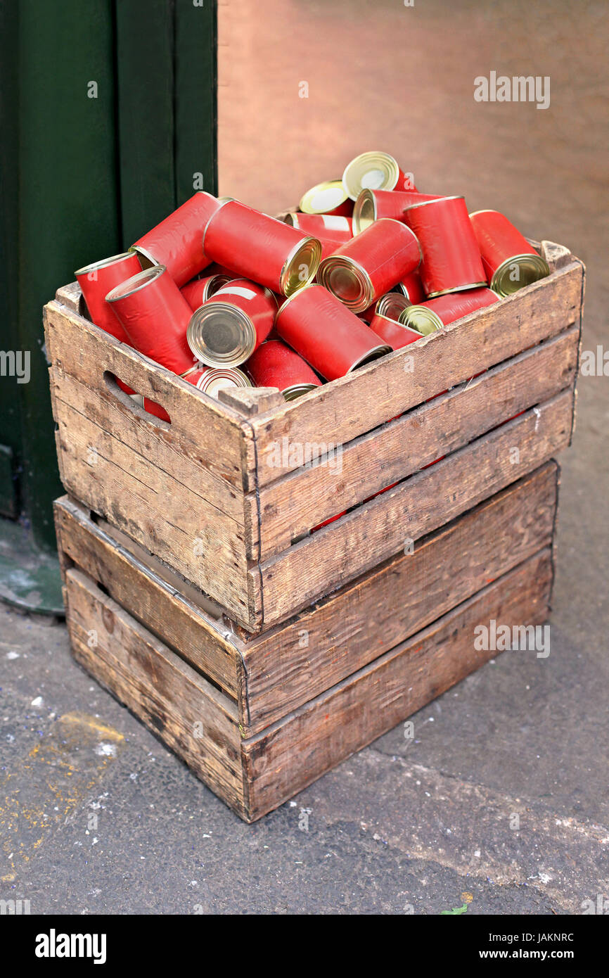 Red cans food inside wooden crate on market Stock Photo - Alamy