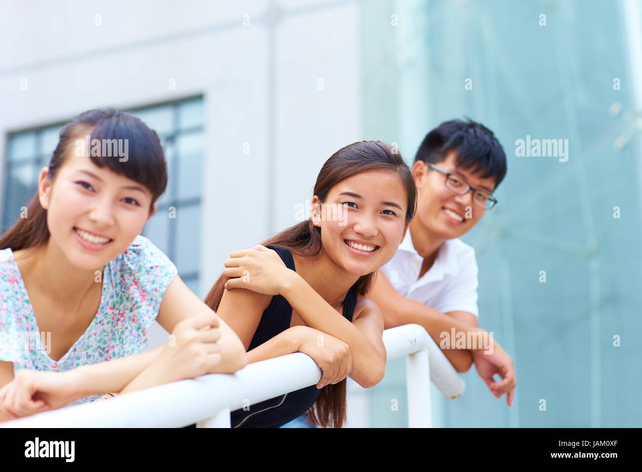 three happy young Chinese or asian college students looking at camera ...