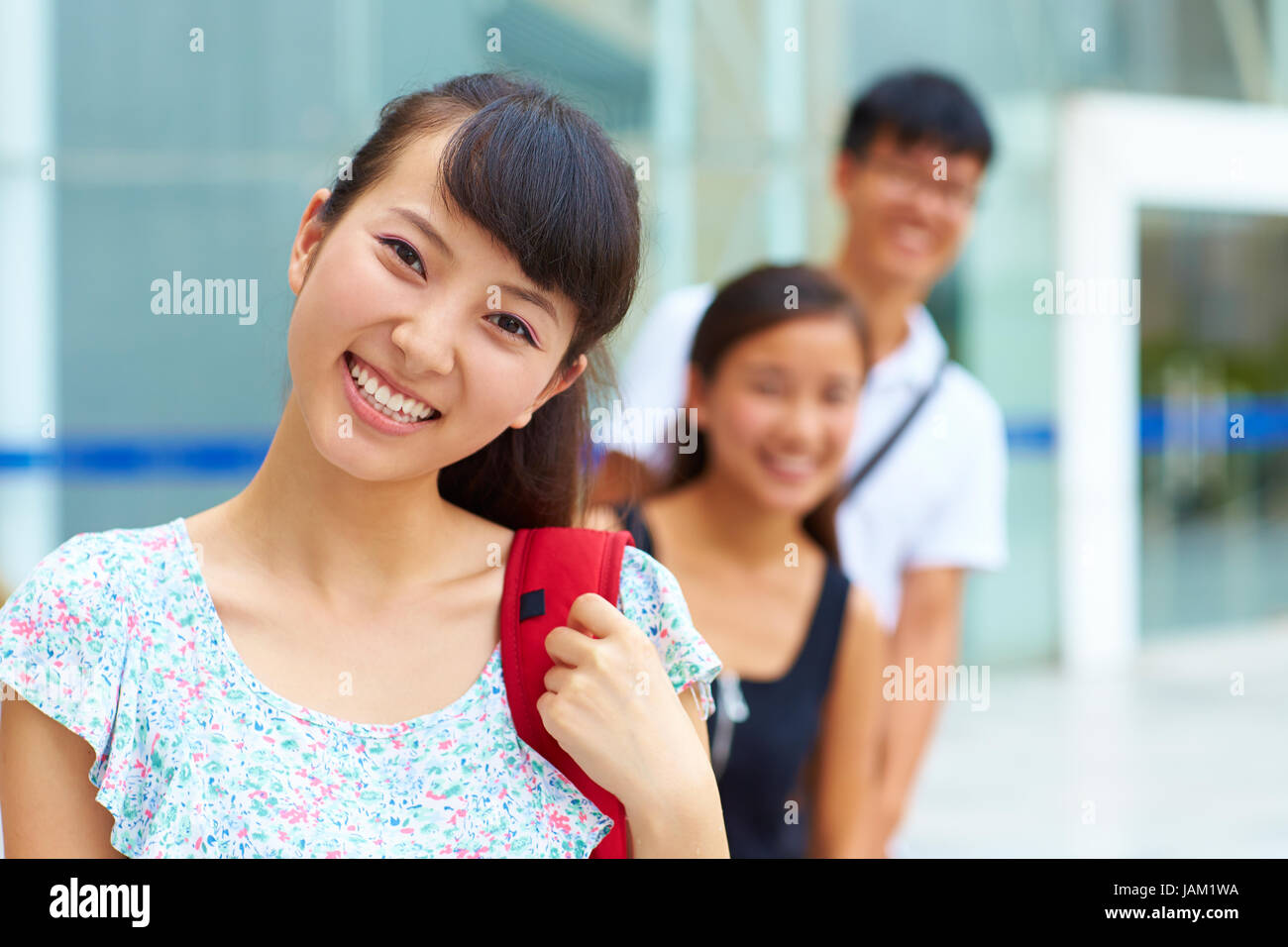 three happy young Chinese or asian college students looking at camera ...