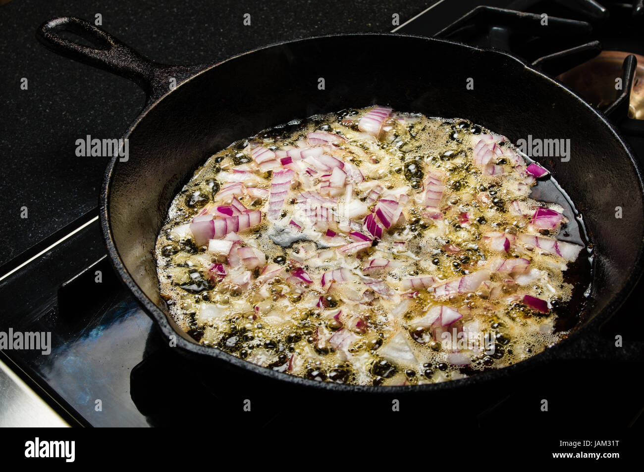 Carmelizing cut red onions in a cast iron skillet Stock Photo - Alamy