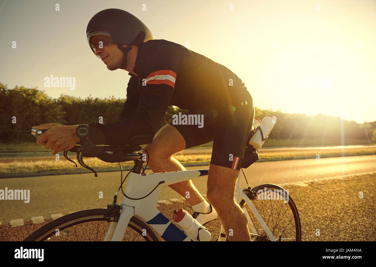 Side view of a person on a cycle moving on the empty evening highway ...