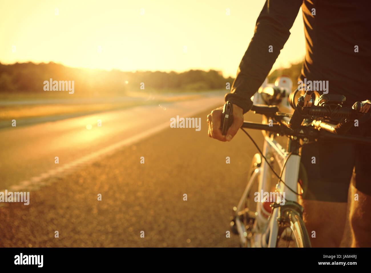 Horizontal crop shot of the biker standing and holding the cycle while ...