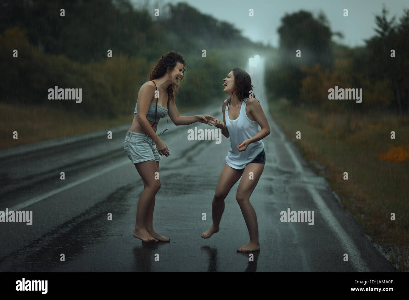 Girls standing in the rain on the roadway Stock Photo - Alamy