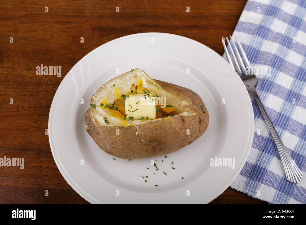 A hot baked potato on a white plate and wood table Stock Photo - Alamy