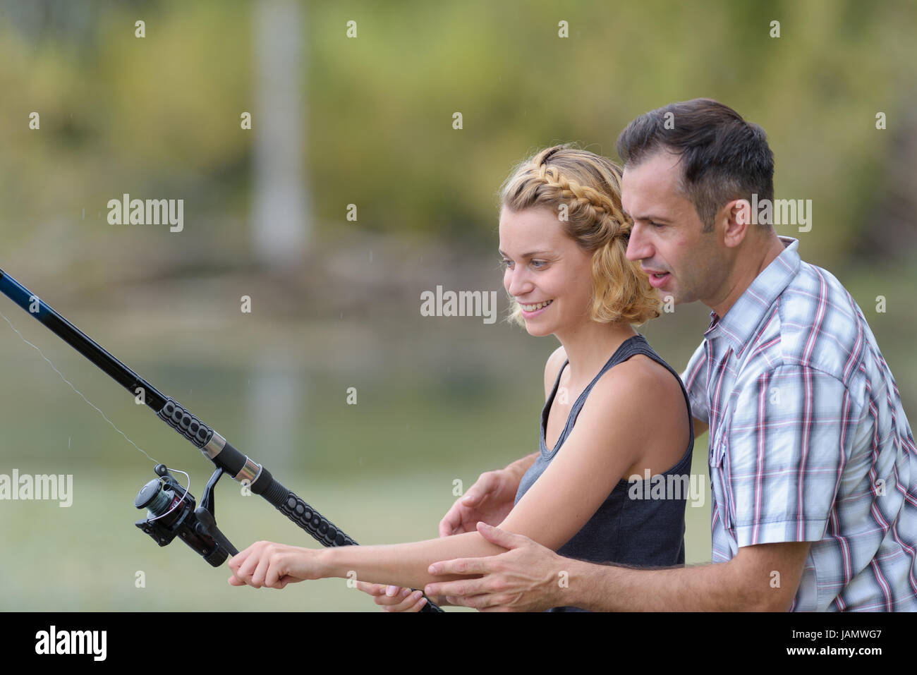 boyfriend teaches his girlfriend to use a fishing rod Stock Photo - Alamy