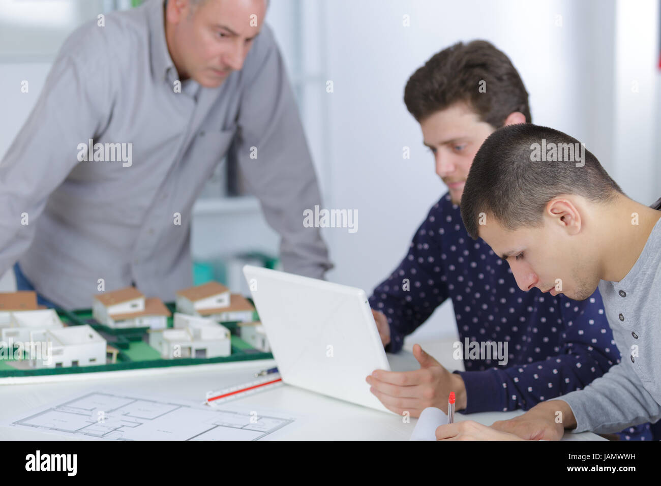students and teacher at their desk with laptop and model Stock Photo ...