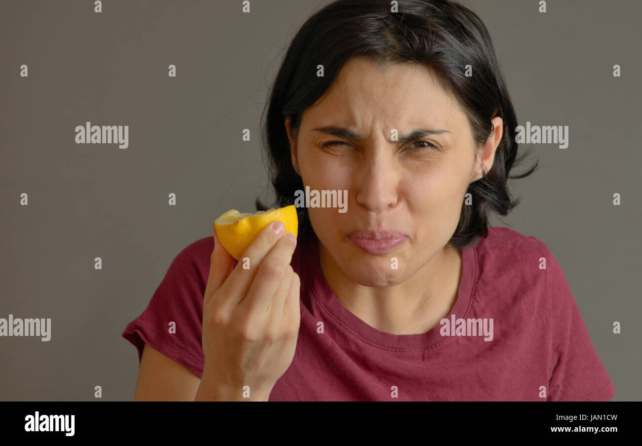Woman eating lemon and making silly faces Stock Photo - Alamy