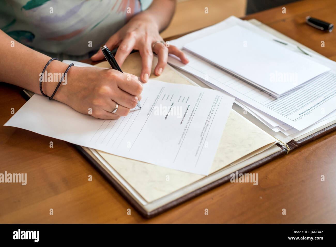 elegant bride signing register, holding pen and official document ...
