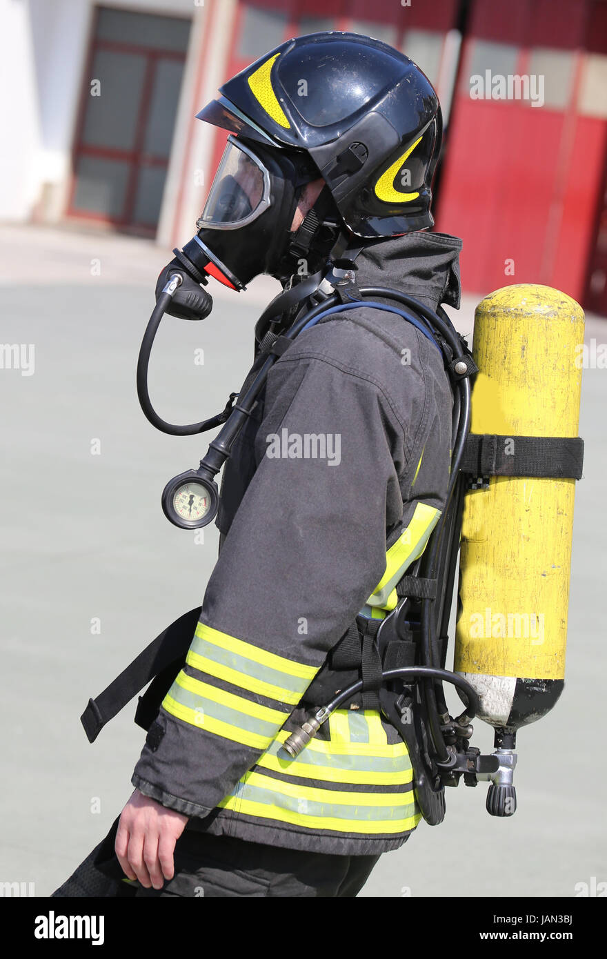 Firefighter with large yellow oxygen cylinder and automatic respirator ...