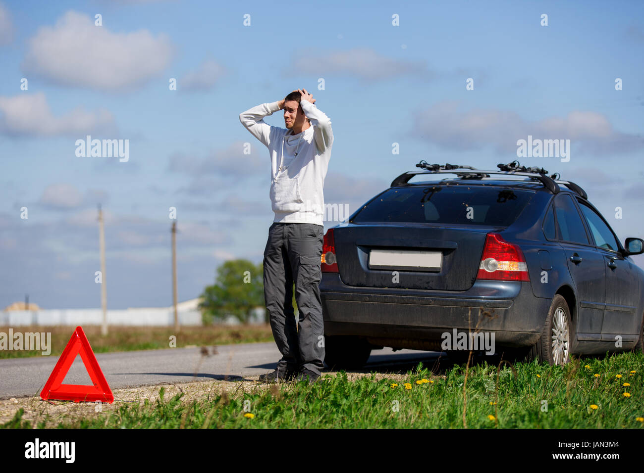 Sad man near broken car puts road sign on road Stock Photo - Alamy