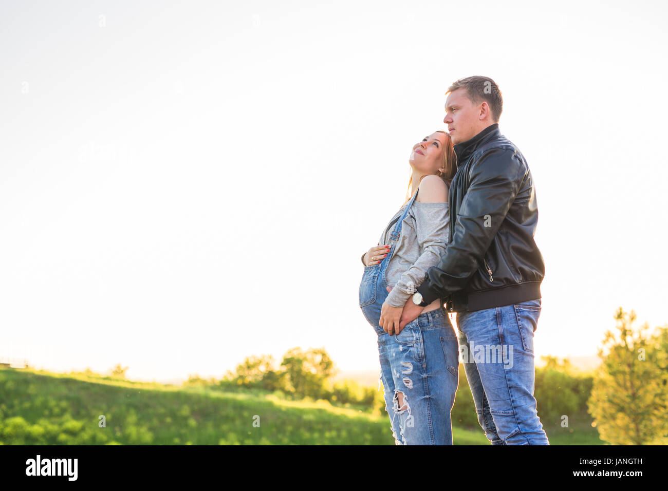 Happy young pregnant couple hugging in nature Stock Photo - Alamy