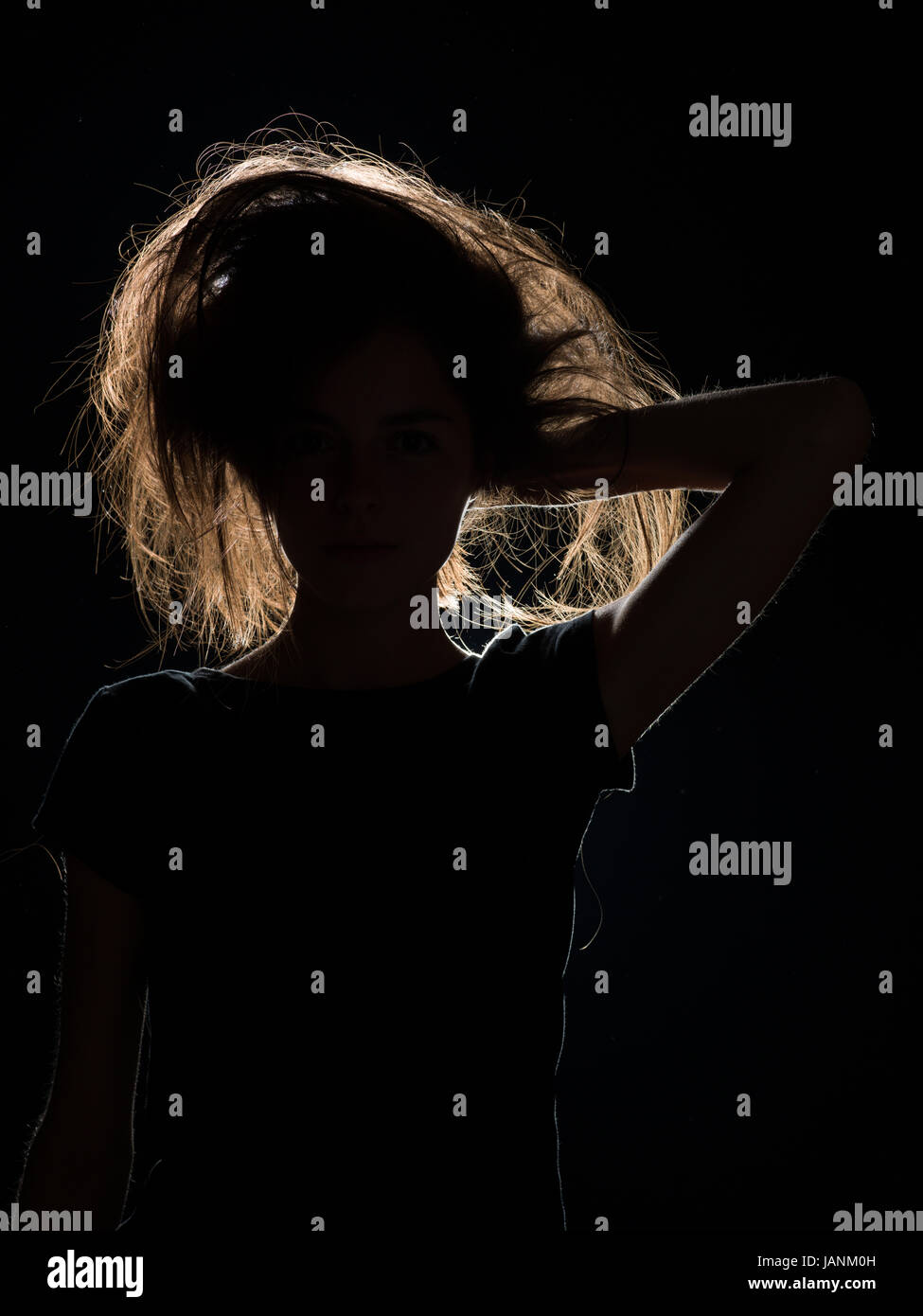 front view of woman in black shadow with messed up hair, on black ...