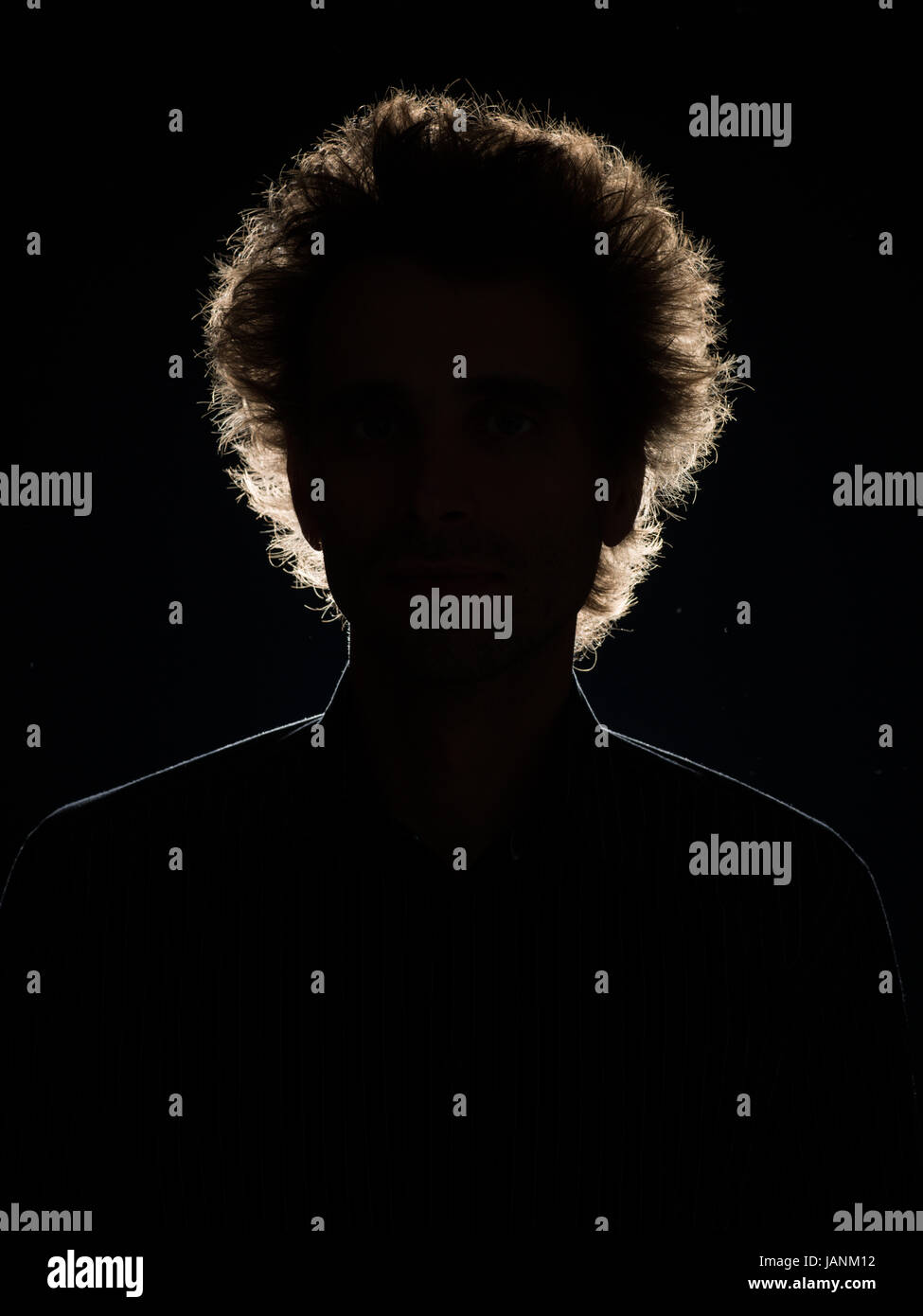front view of man in shadow with back lighting on black background ...
