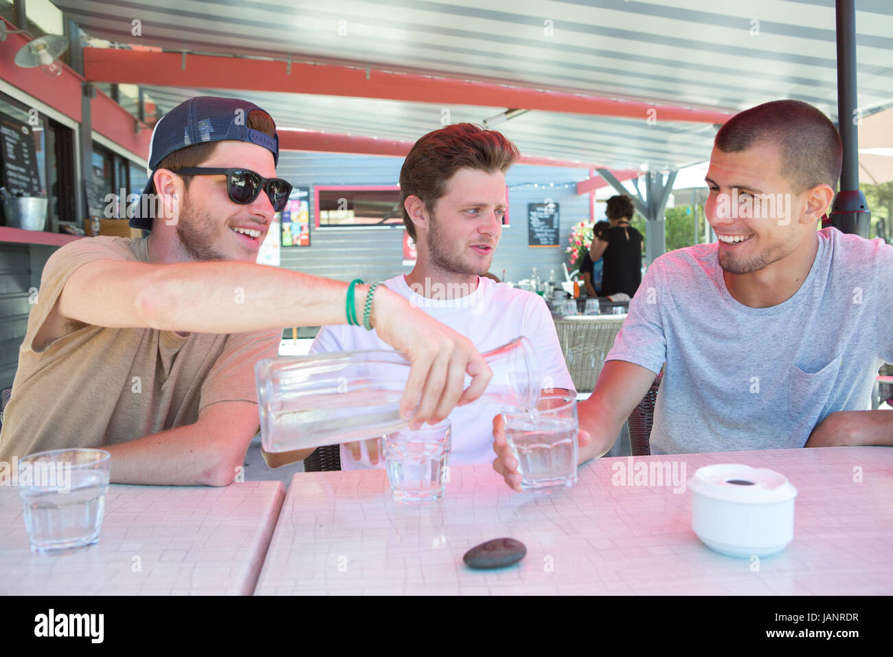 happy man with friends pouring water at restaurant Stock Photo - Alamy