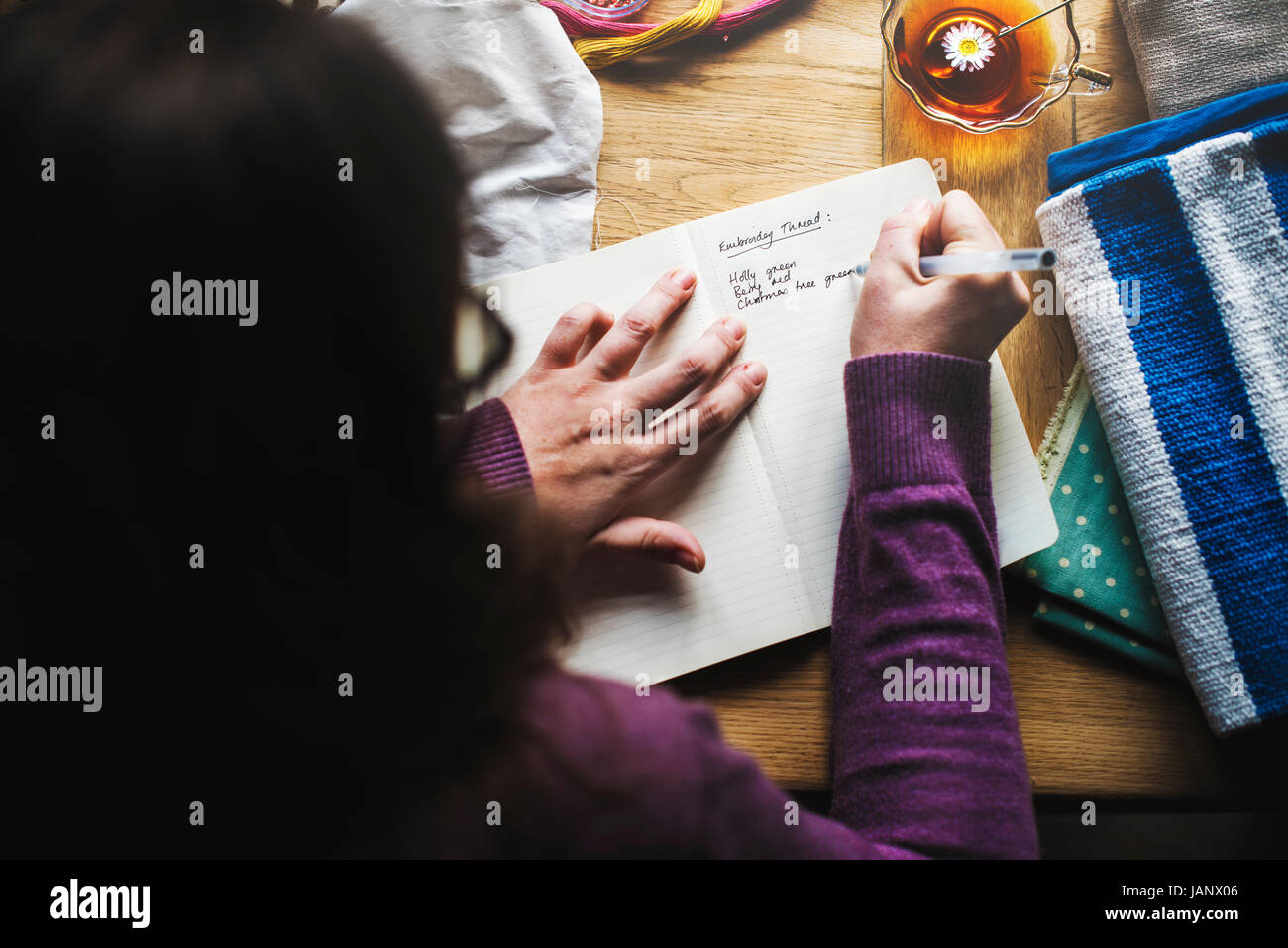 Aerial view of woman writing thread color list on notebook Stock Photo ...