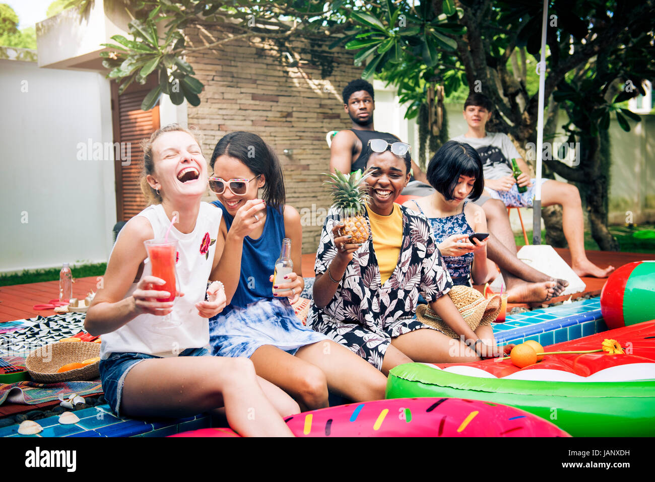 Group of diverse women sitting by the pool with inflatable tubes Stock ...
