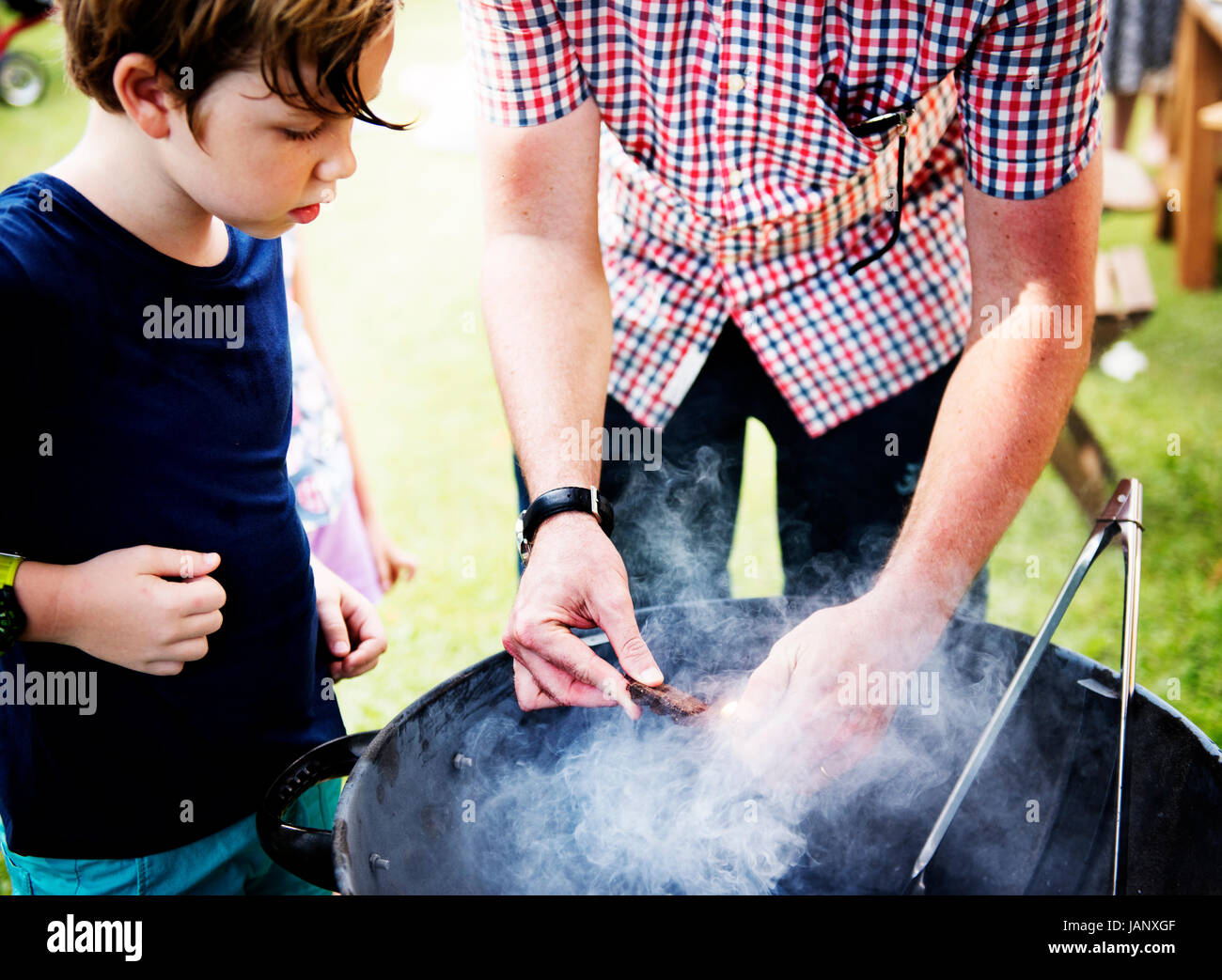 Closeup of father preparing charcoal grill for barbecue party with son ...