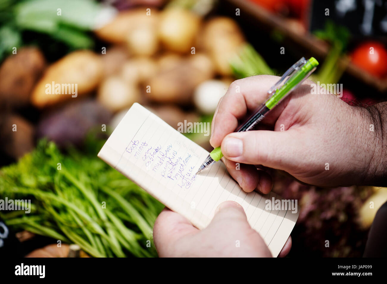 Closeup of hands writing vegetable list on notebook Stock Photo - Alamy