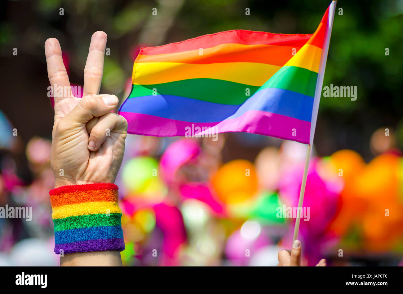 Supporting hand makes peace sign in front of a rainbow flag flying on ...