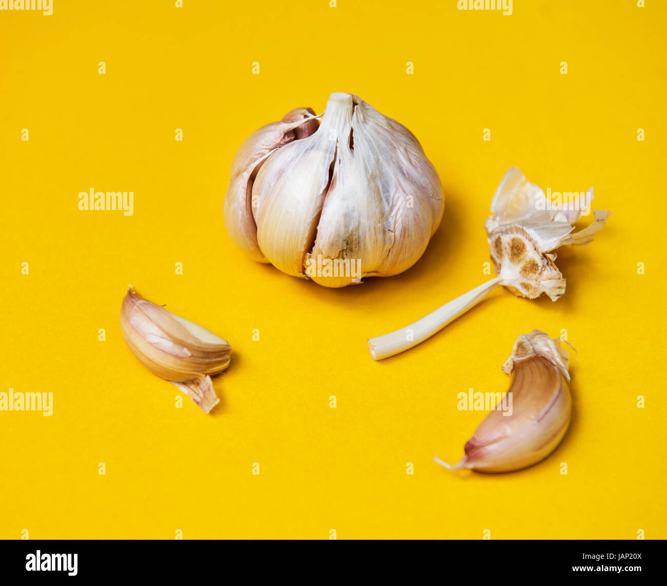 Closeup of garlic cloves on yellow background Stock Photo - Alamy