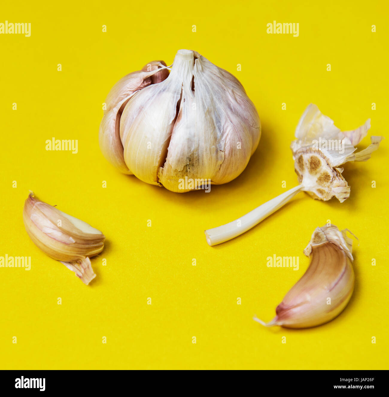 Closeup of garlic cloves on yellow background Stock Photo - Alamy