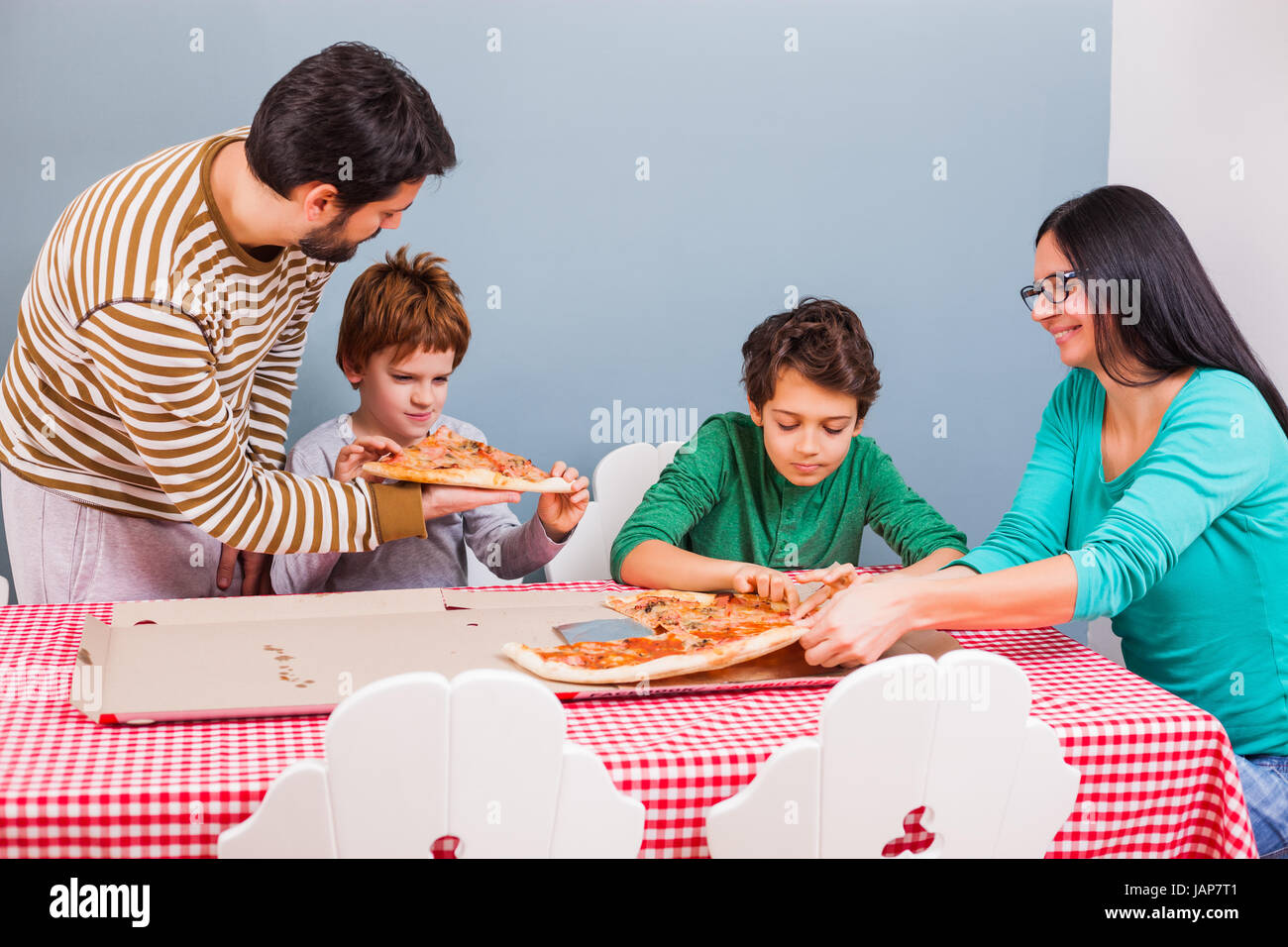 Parents and their two sons are eating pizza at home Stock Photo - Alamy