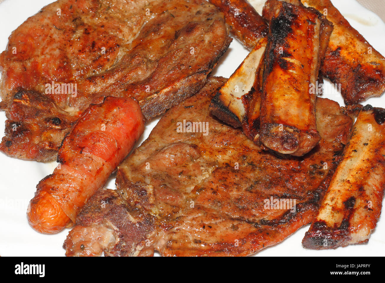 Verschiedene Sorten von gegrilltem Fleisch und Wurst auf einem Teller ...