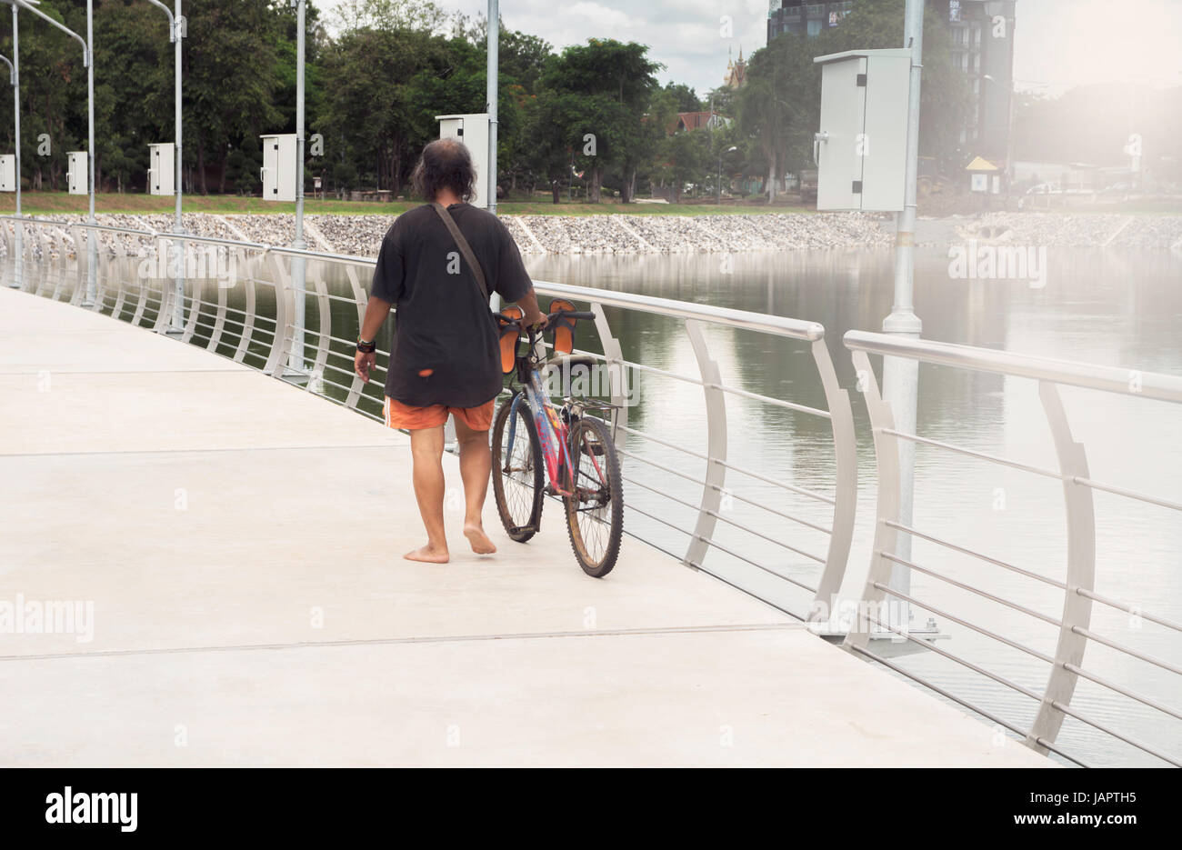 Long hair man walking and pull bicycle on street Stock Photo - Alamy