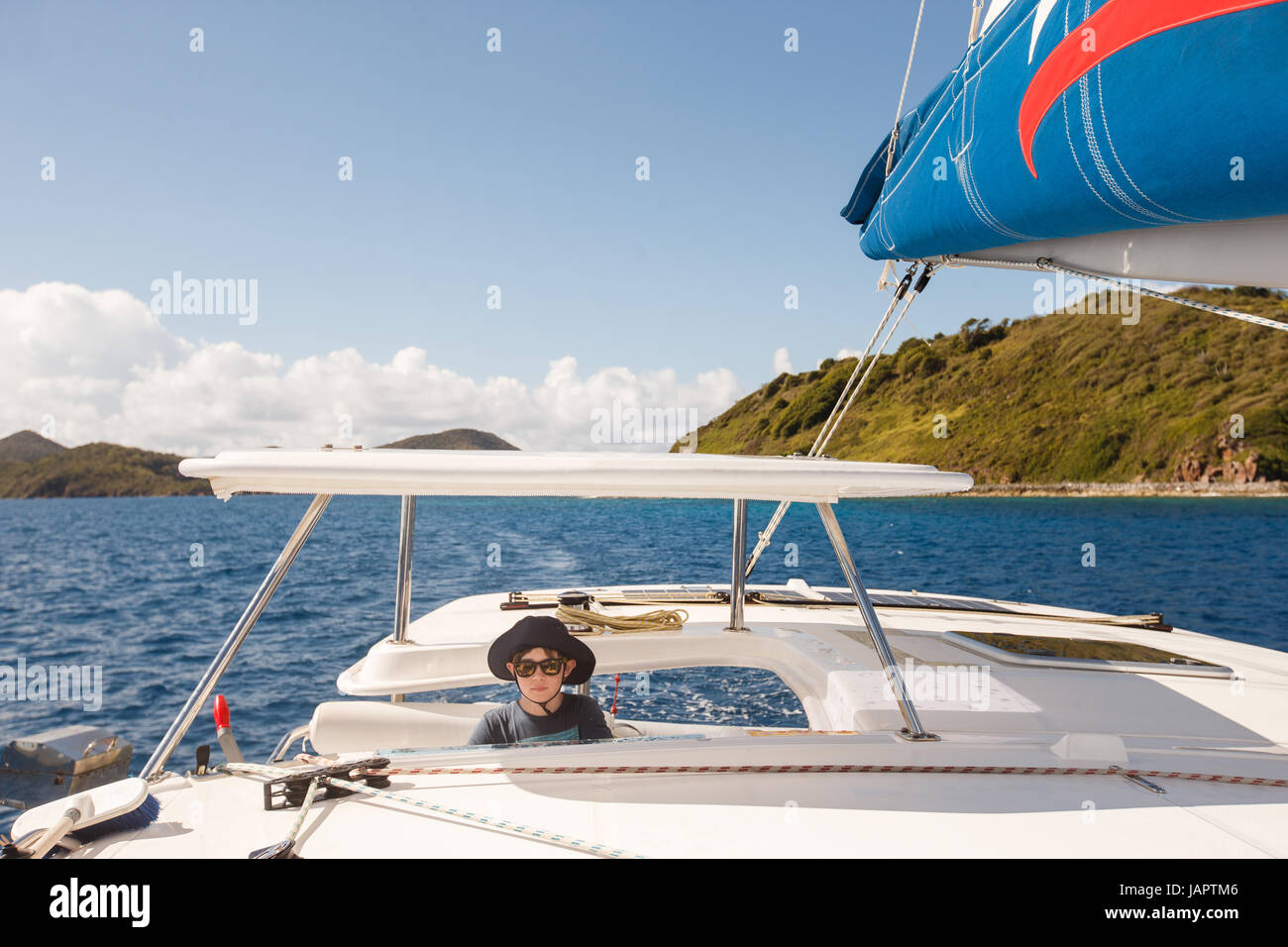 boy as captain at the help driving a catamaran sailing in the caribbean ...