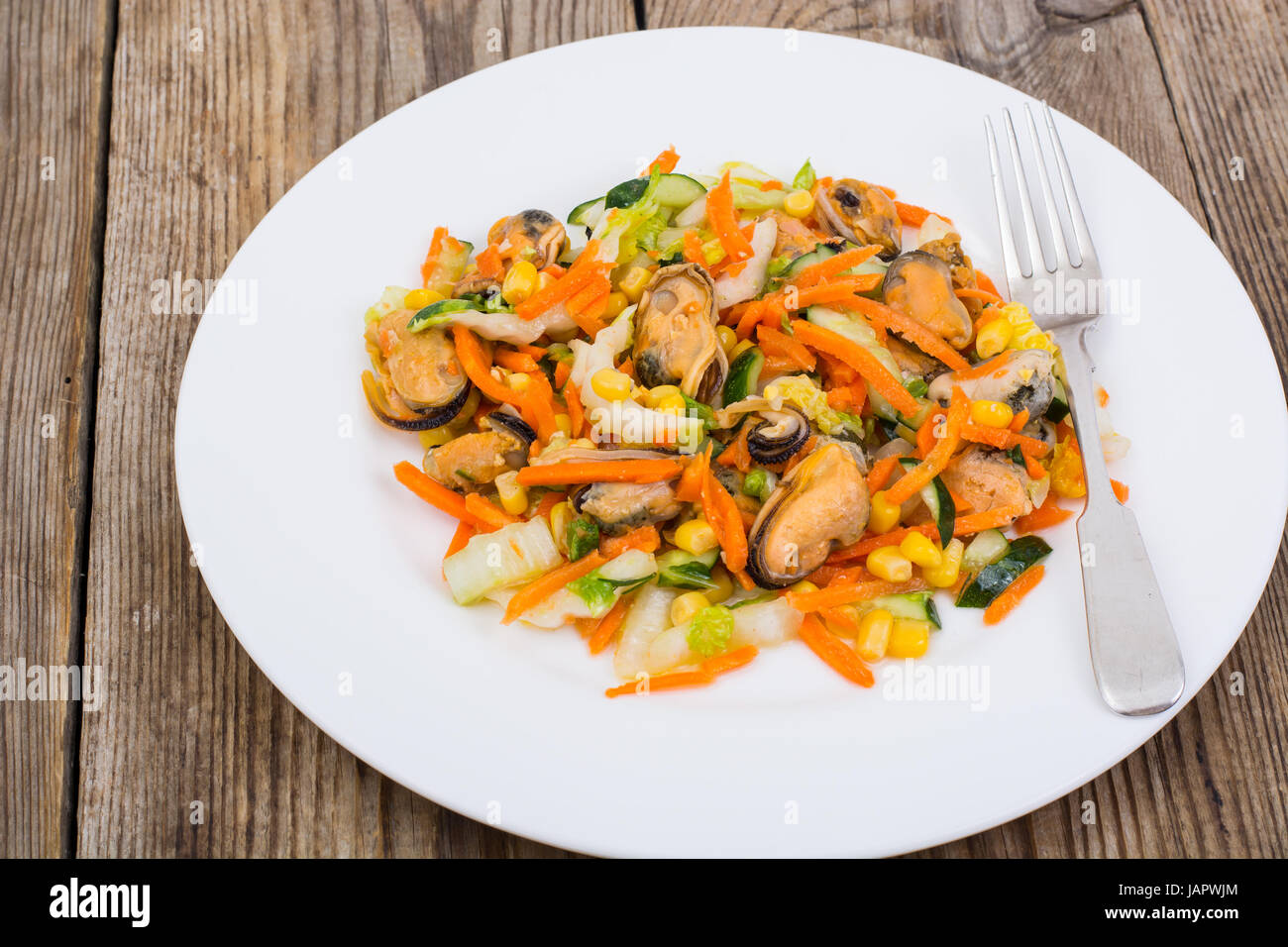 Peking cabbage, corn, cucumber, mussels on a white saucer on an Stock ...