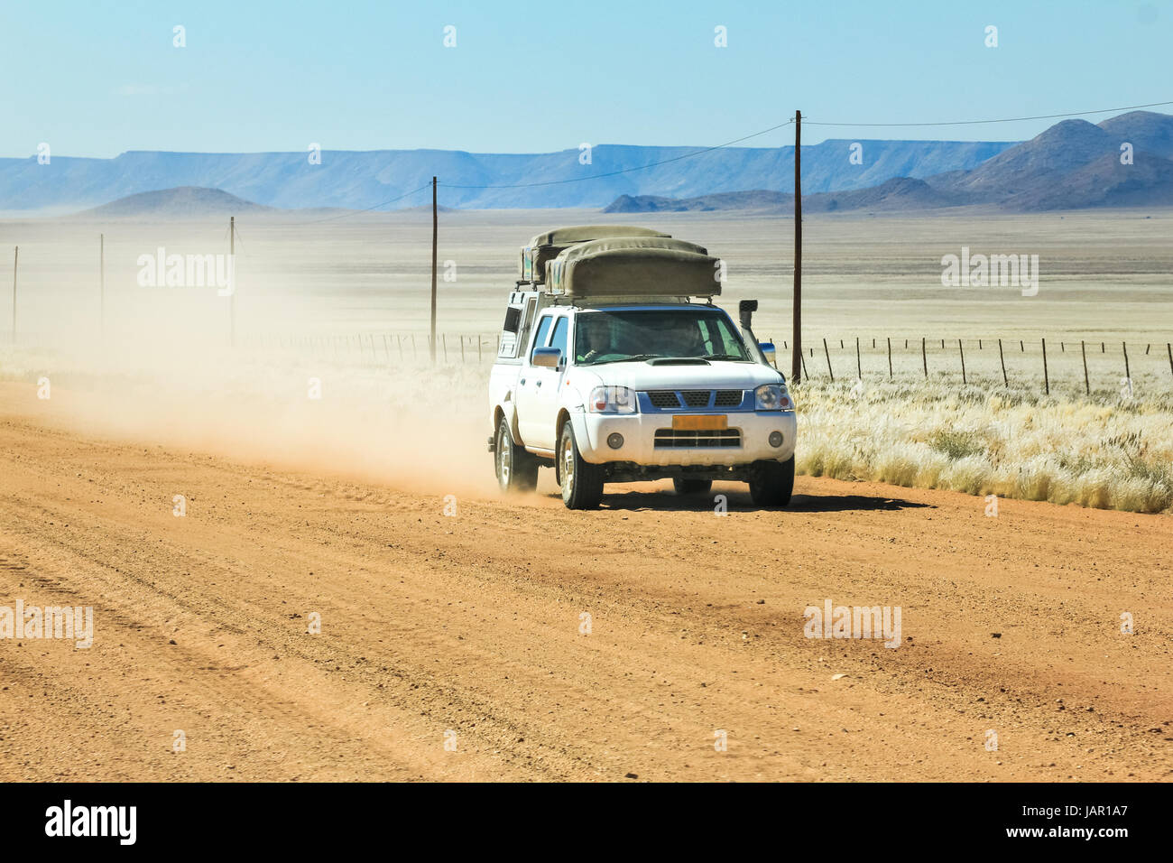 Pickup truck driving fast with dust cloud on desert road Stock Photo ...